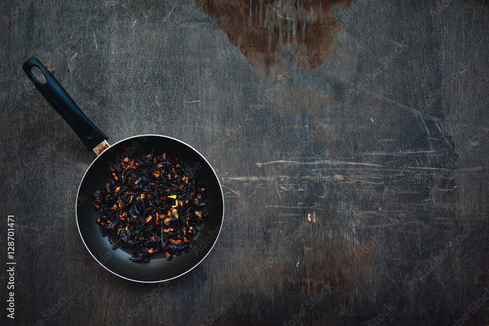 The failure on kitchen: burnt charred vegetables in frying pan on dark ...