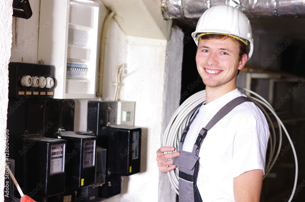 sympathischer, junger Elektriker bei der Arbeit Stock-Foto | Adobe Stock