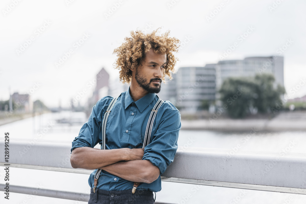 Young man leaning on railing with arms crossed Stock Photo | Adobe Stock