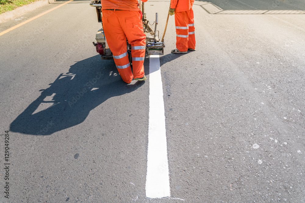Thermoplastic spray marking machine during road construction. Worker ...