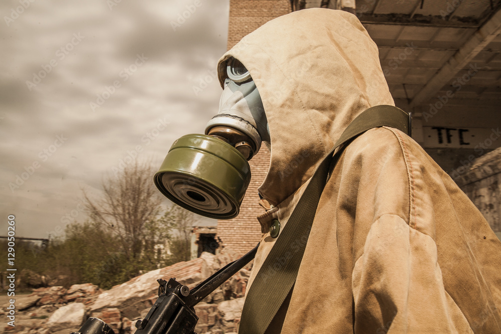 young boy stands with a gun in his hand. boy in a gas mask. boy in a ...