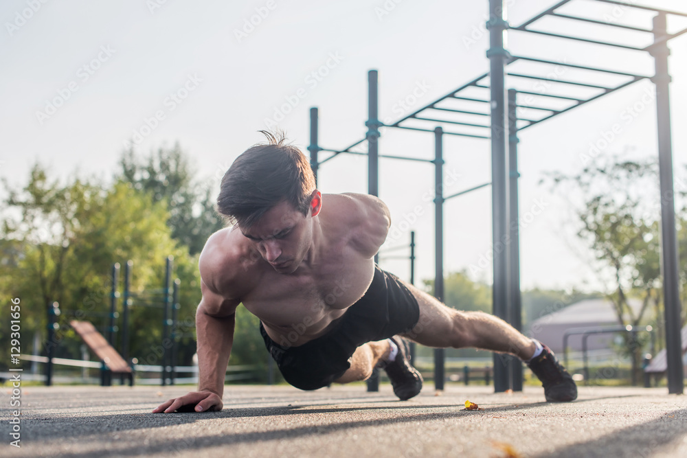 Athlete young man doing one-arm push-up exercise working out his upper ...
