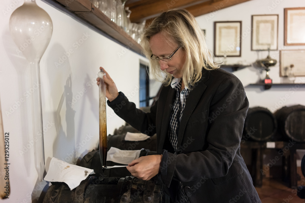 Woman serving herself test sample of balsamic condiment for tasting ...