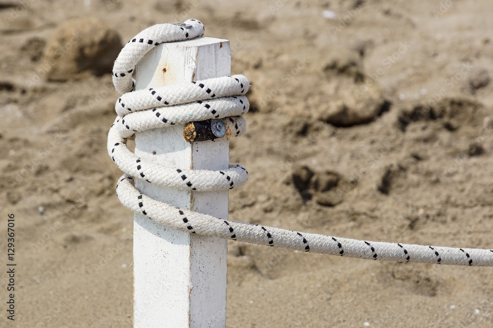 Post with a rope tied around it the beach in background Photos | Adobe ...