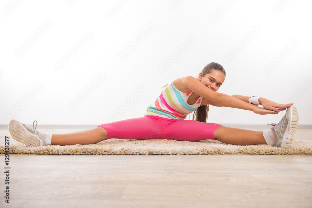 Beautiful teenage girl doing stretching exercises, girl on the carpet ...