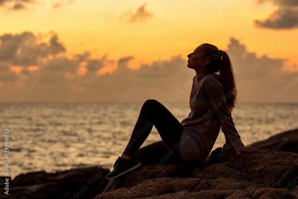 Young woman sit on the beach at sunrise sea in the background Stock ...
