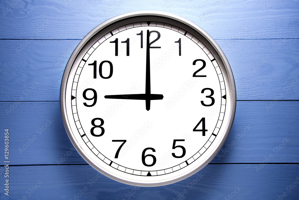 Round clock shows shows at 9 o'clock, clock on blue background Stock 写真 ...