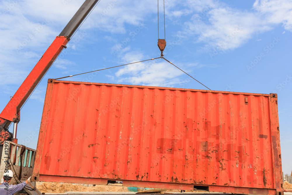 Mobile crane operating by lifting and moving a heavy office container ...