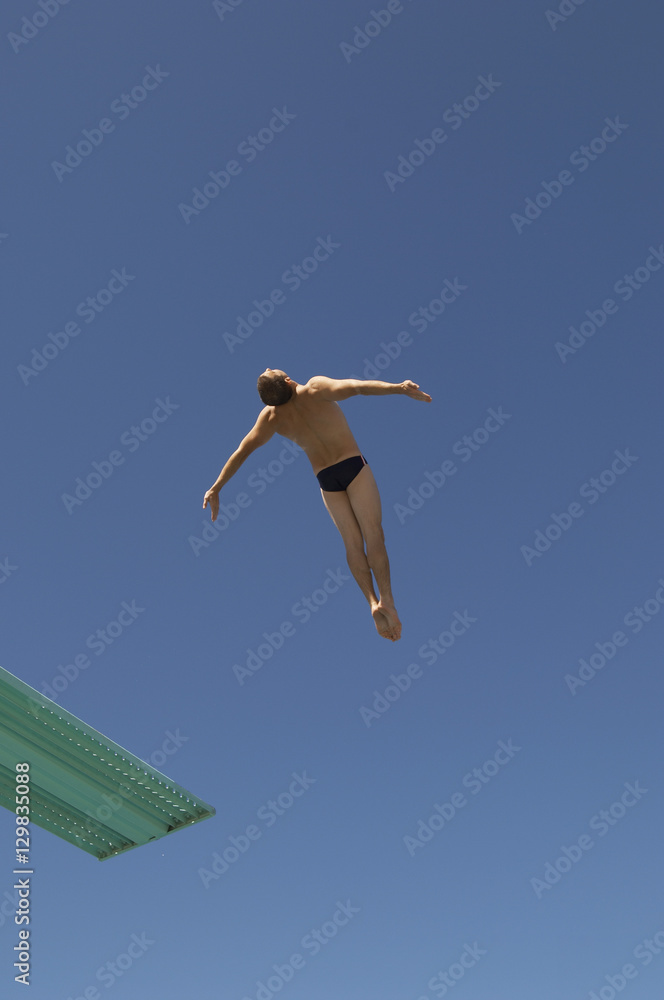 Full length of a male diver diving backwards in midair Stock Photo ...