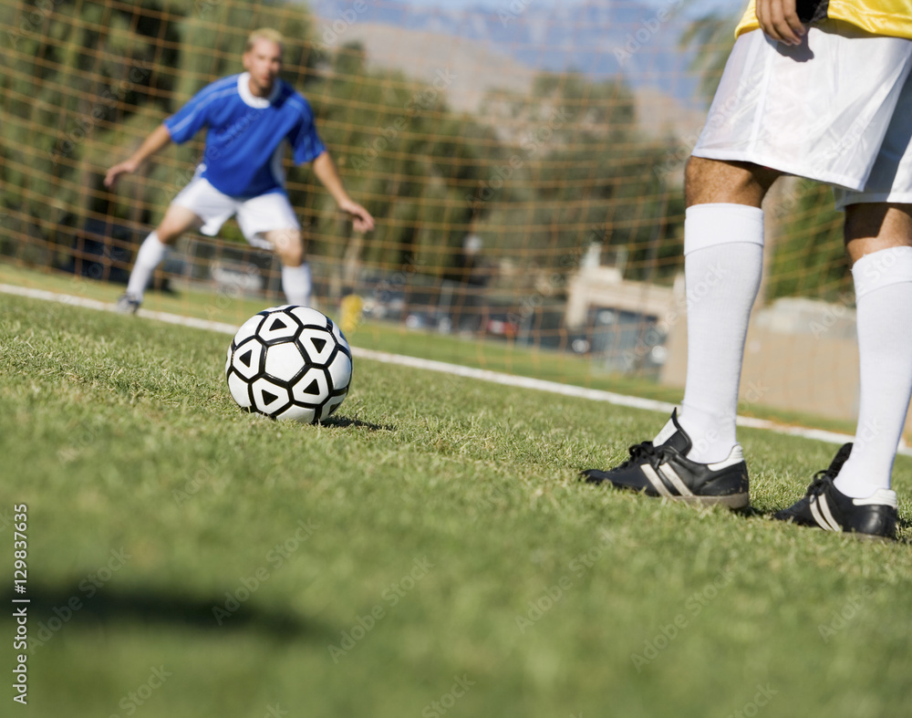 Goalkeeper stands still as a soccer player in position to kick ball ...