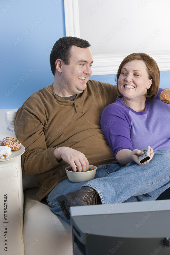 Happy obese couple watching television together at home Stock Photo ...