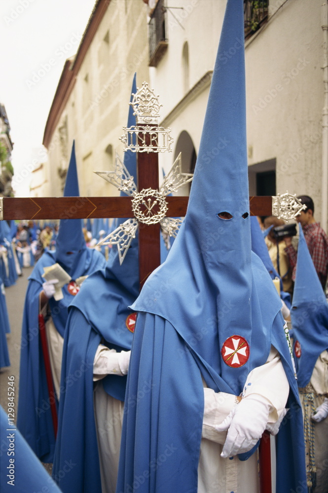 Hooded penitents around a cross in the Holy Week procession in Seville ...