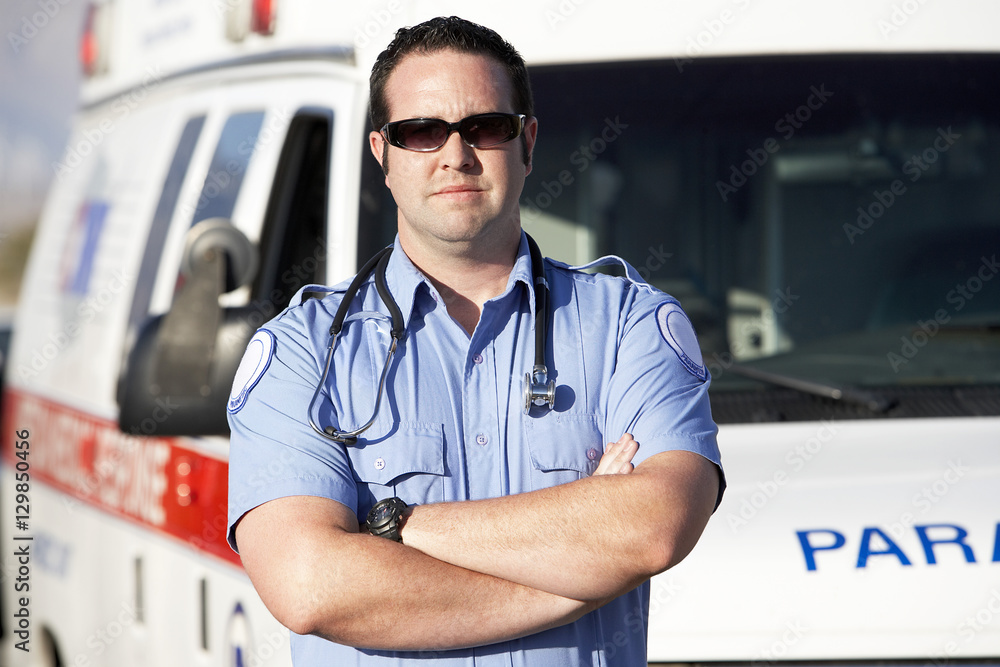 Portrait of a confident male paramedic worker standing in front of an ...