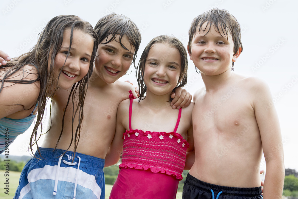 Portrait of four happy wet children in swimsuits standing against the ...