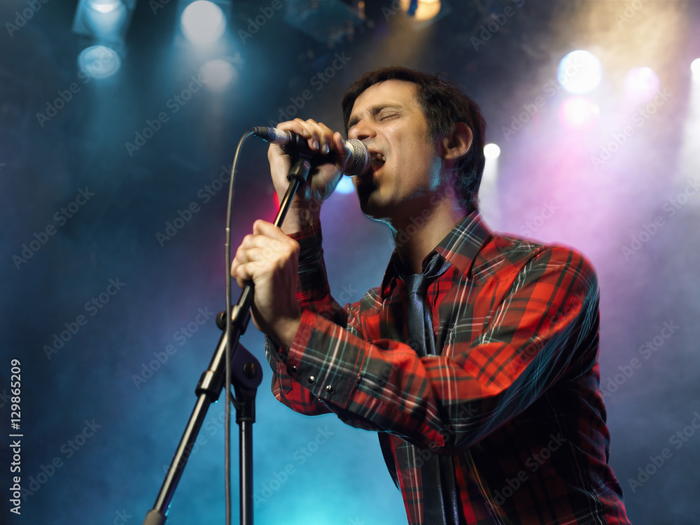 Low angle view of a young man singing into microphone on stage Stock ...