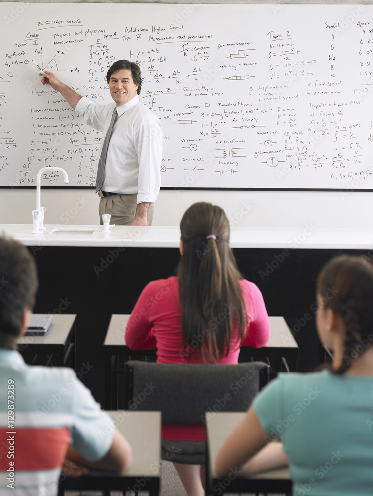 Teacher teaching on whiteboard to high school students in classroom ...