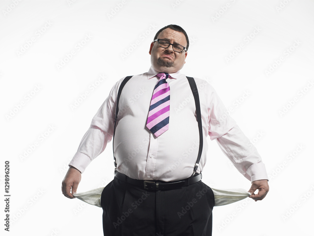 Portrait of an overweight businessman pulling out empty pockets against ...