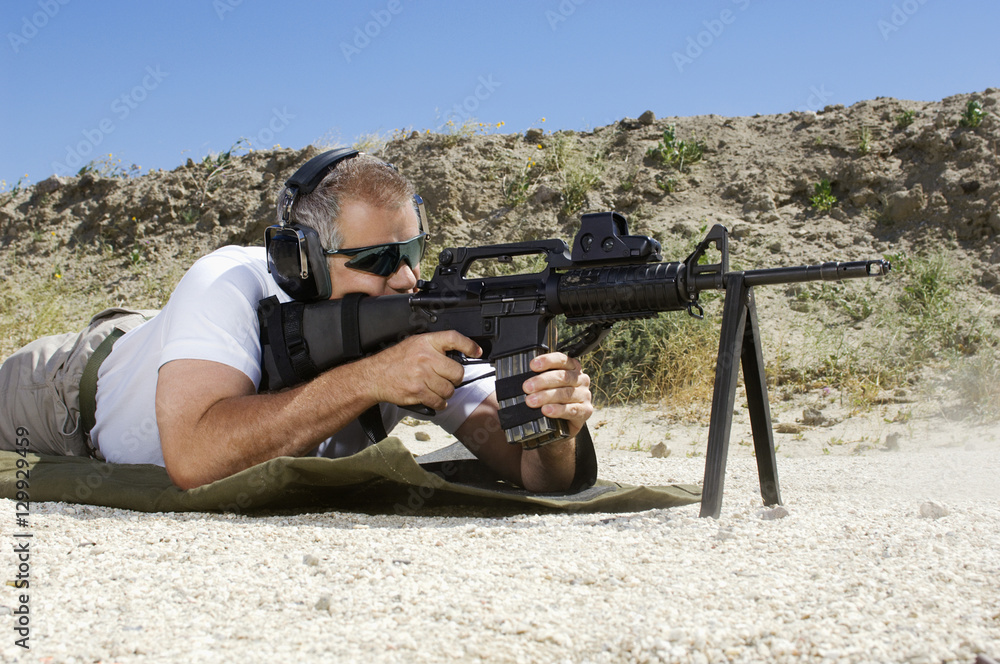 Man lying on ground aims machine gun at firing range during combat ...