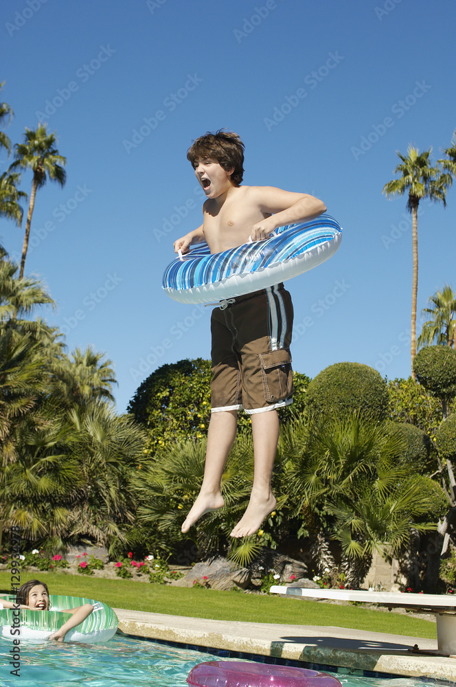 Teenage boy jumping into swimming pool with inflatable raft Stock Photo ...