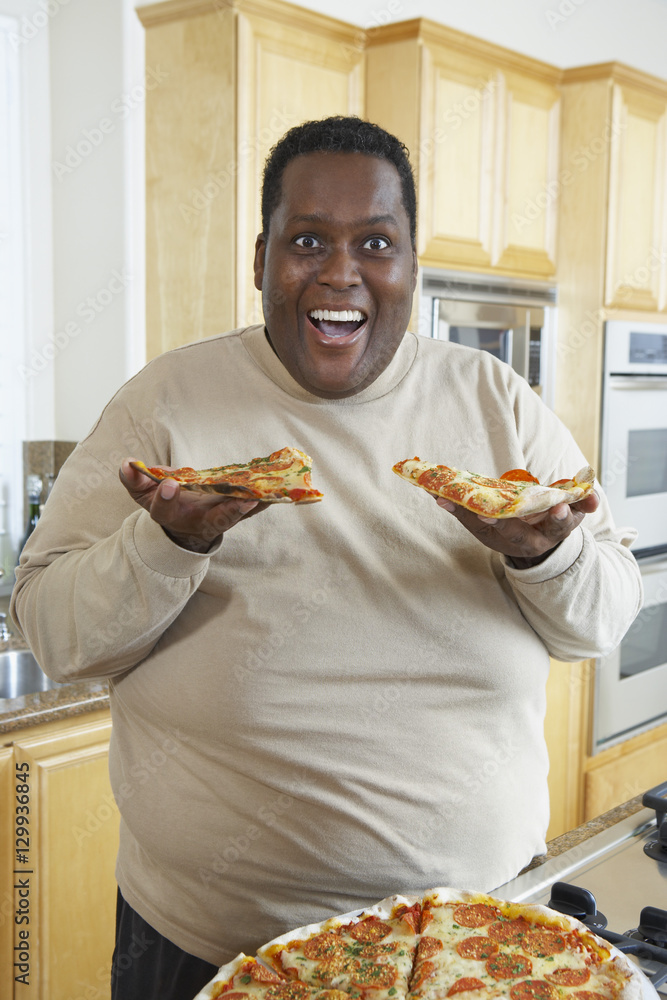 Portrait of an excited obese African American man holding slices of ...