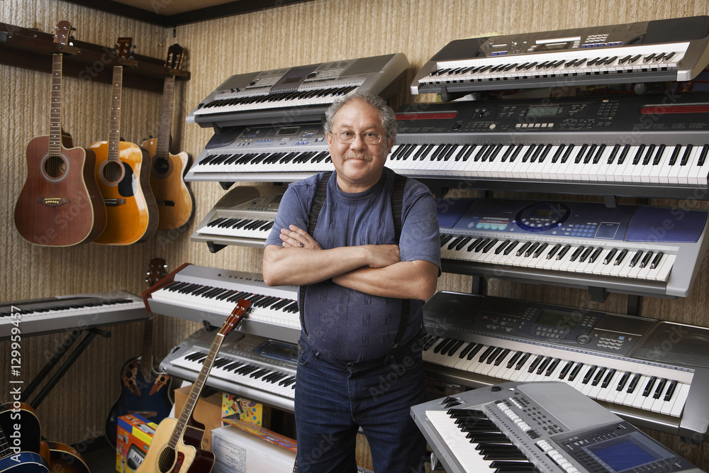 Portrait of middle aged male music store owner standing arms crossed ...