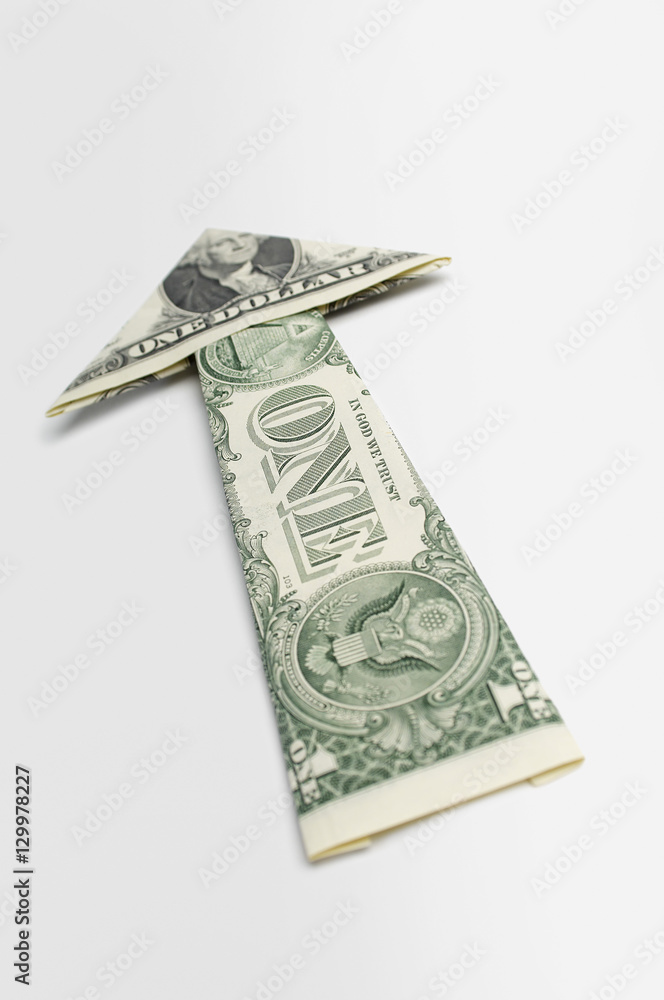 Arrow sign made of dollar bill pointing upwards against white ...