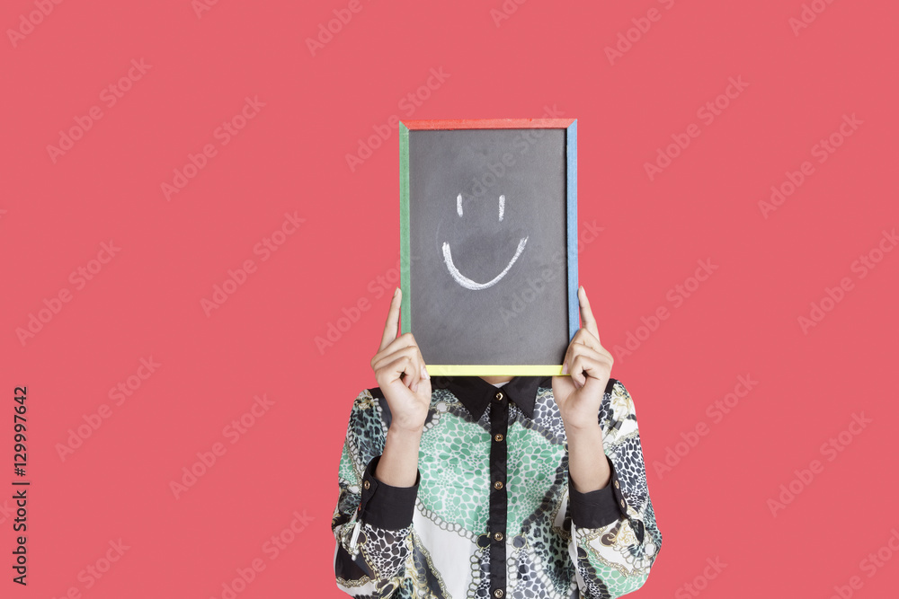 Teenage boy holding smiley face sign over pink background Stock Photo ...