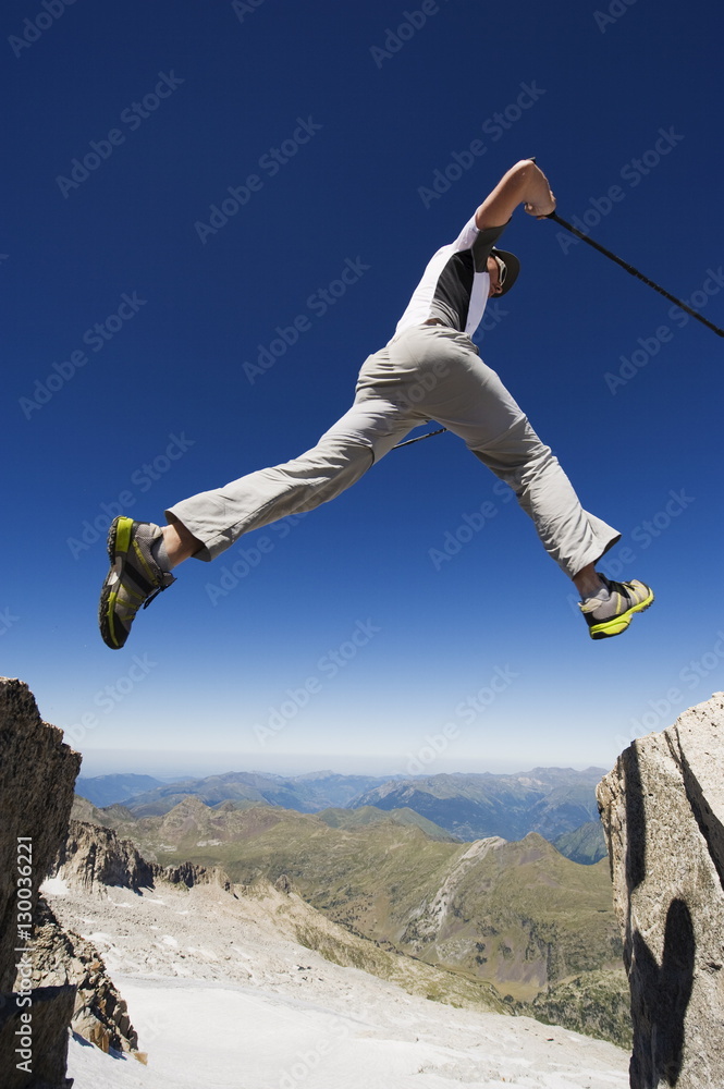 Hiker jumping across a gap in the rocks, Pico de Aneto, the highest ...
