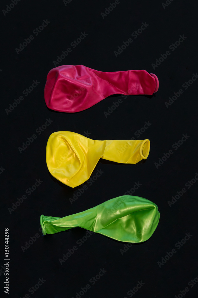 deflated red, yellow and green balloon on black background Stock Photo ...