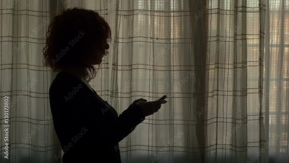 profile of a woman standing in a dark room writing a textmessage vídeo ...