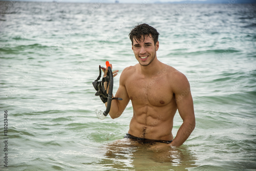 Young muscular handsome man in swimming pants holding diving mask and ...