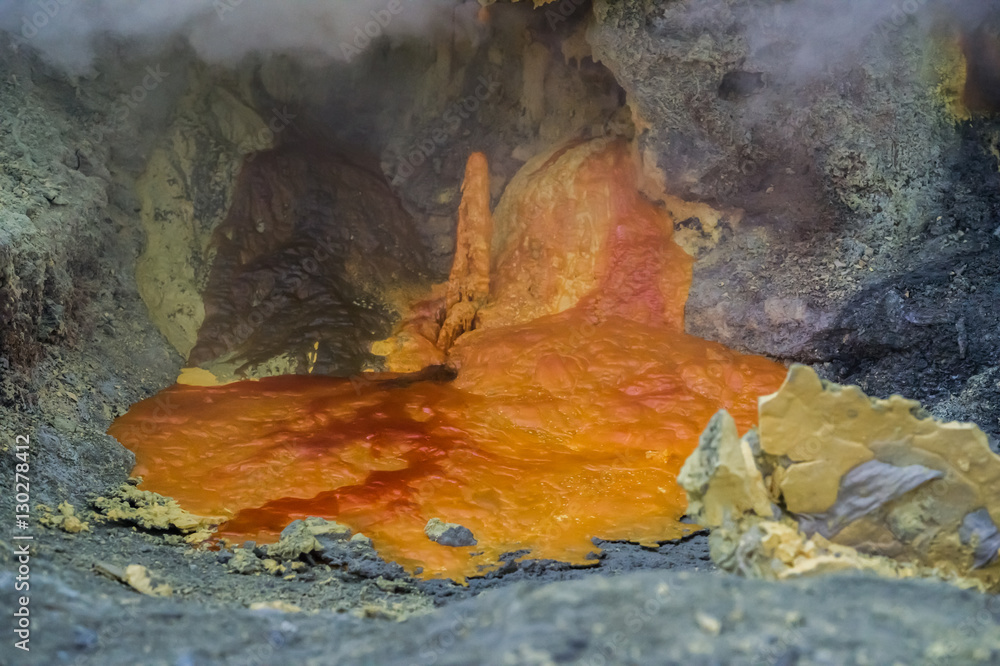 Orange hot lava flows and form puddles on the solidify stone, shrouded ...