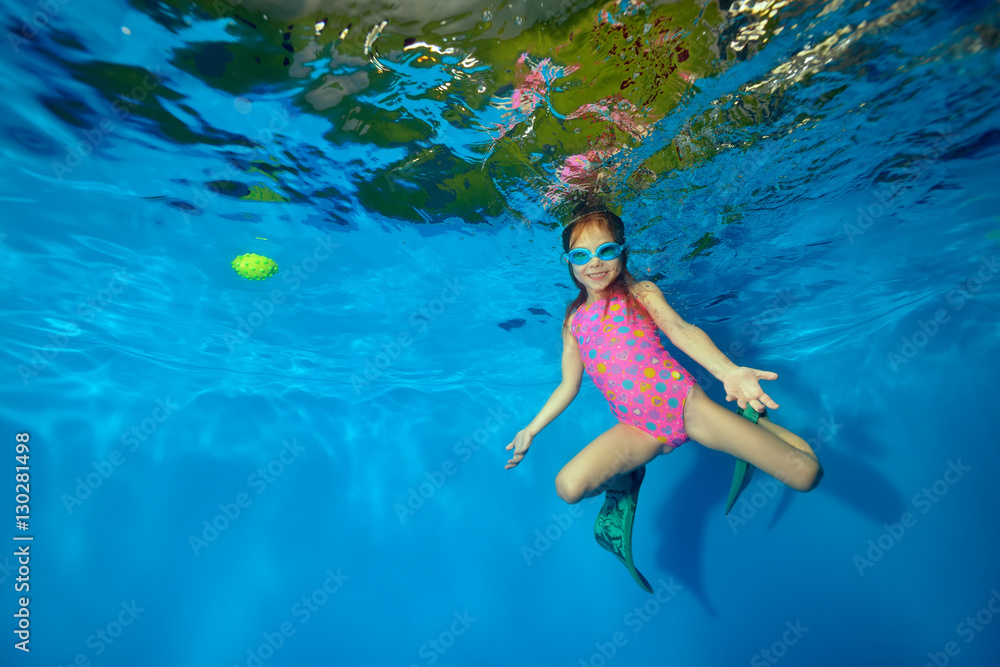 Sports little girl swimming fins underwater in the pool on a blue ...