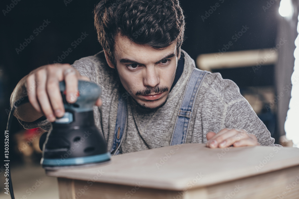 Carpenter using electric sander on plank of wood at workshop Stock ...