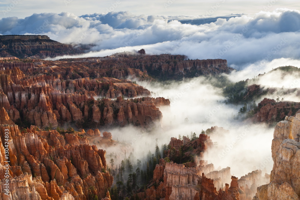 Pinnacles and hoodoos with fog extending into clouds of a partial ...
