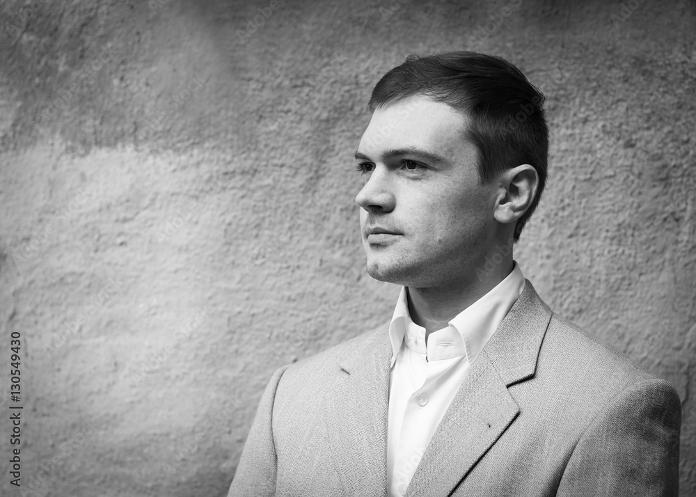 Handsome manly man in a suit on wall background. Black and white ...