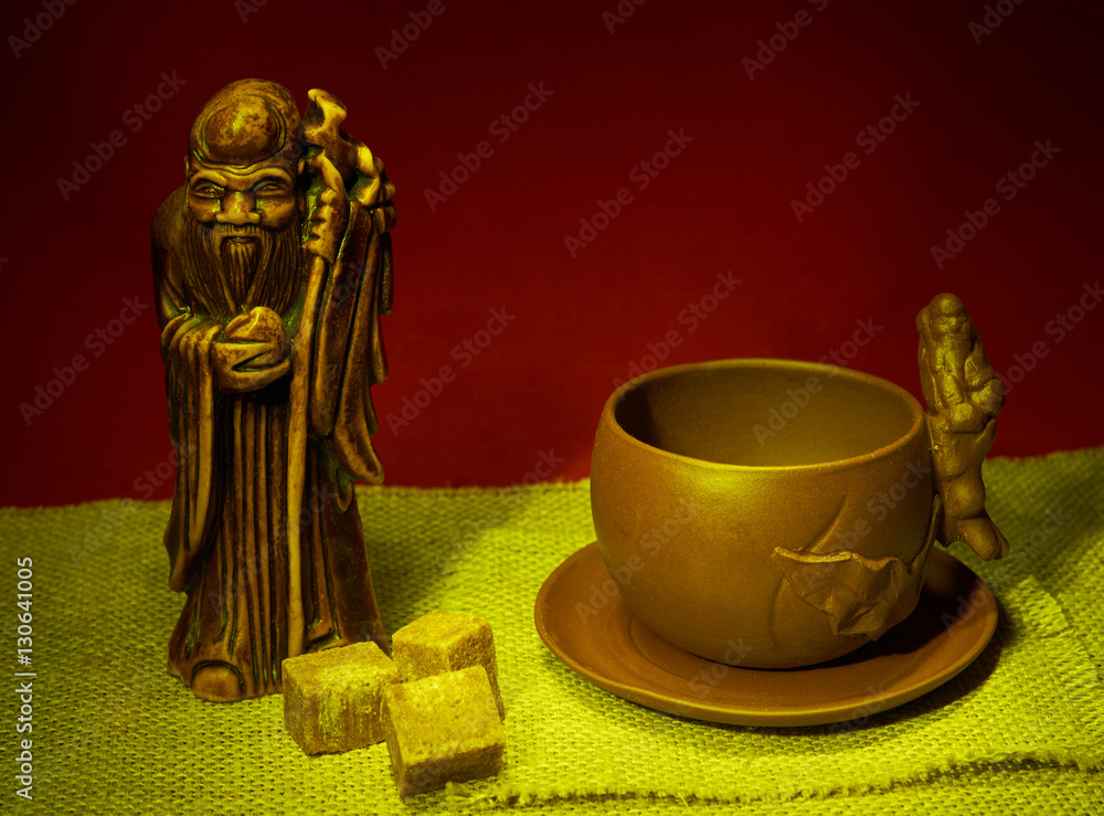 Still life with a statuette of the god of tea, a cup and lumps o Stock ...