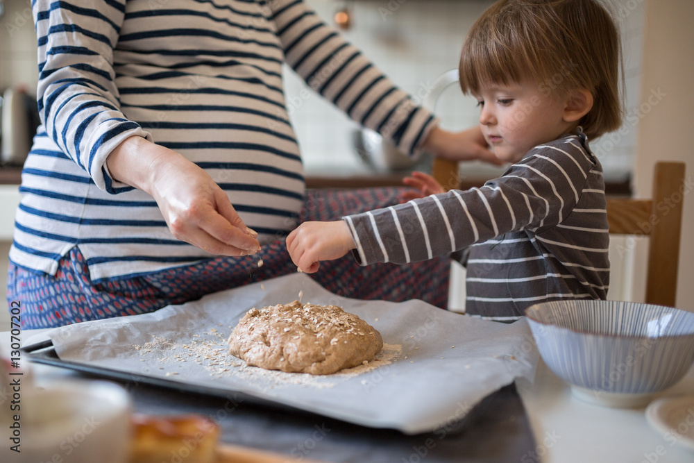 Pregnant mom making bread in kitchen with her son Toddler, hands Stock ...