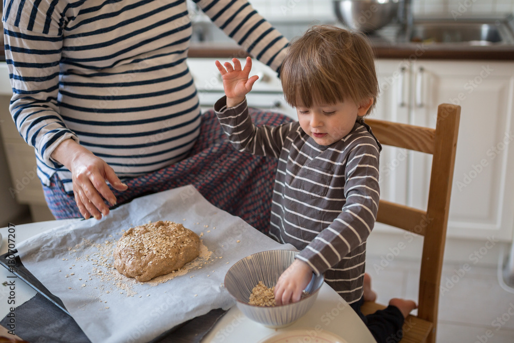 Pregnant mom making bread in kitchen with her son Toddler, hands Stock ...
