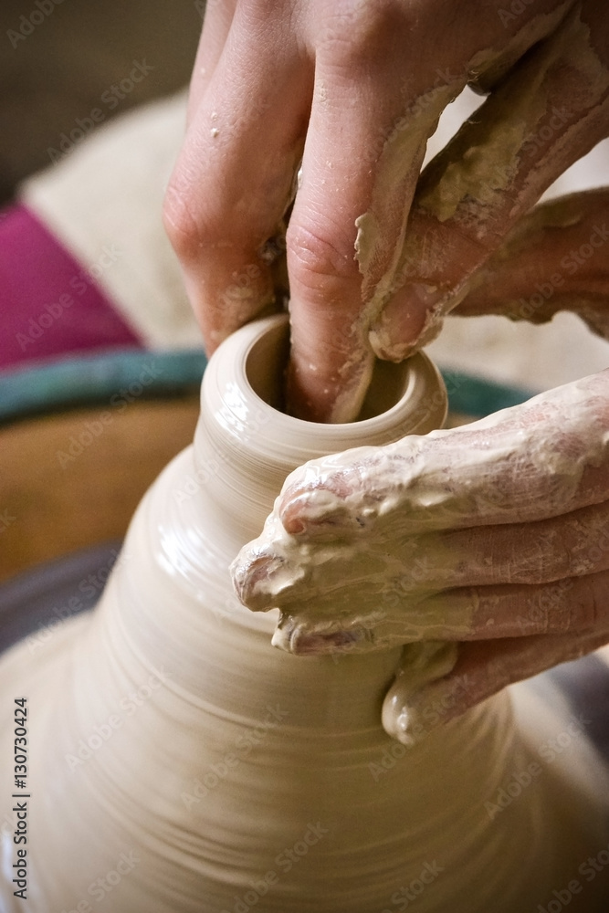 A man with his hands dub wall jug, which he sculpts out of clay on a ...