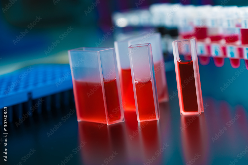 Quartz cuvette for laser chromatography with red liquid. Physical ...