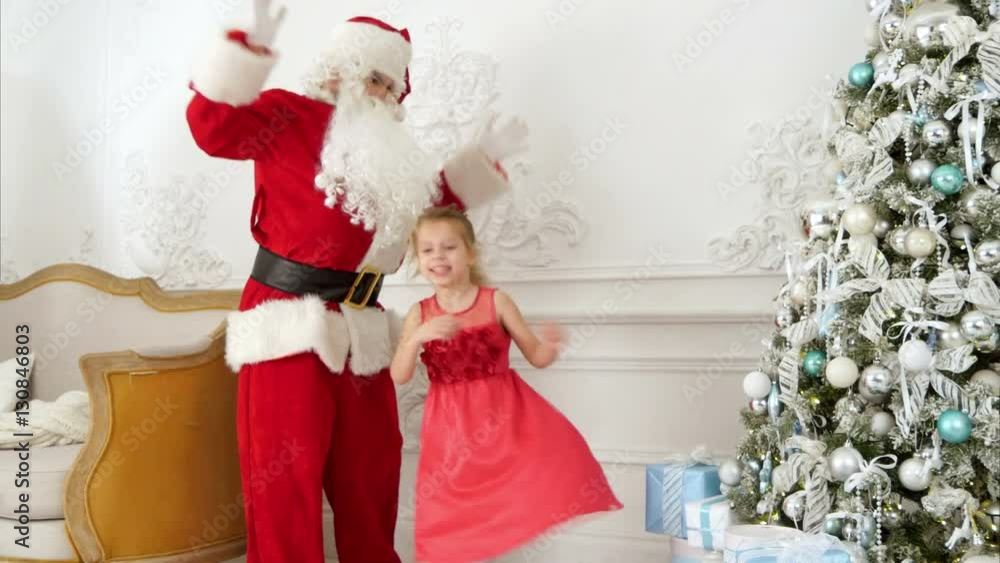 Santa Claus clapping his hands while pretty little girl dancing around ...