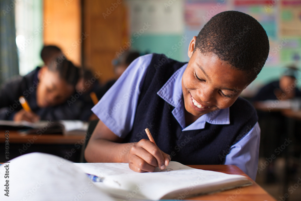 Foto de Young boy doing class work at a desk in a classroom in South ...