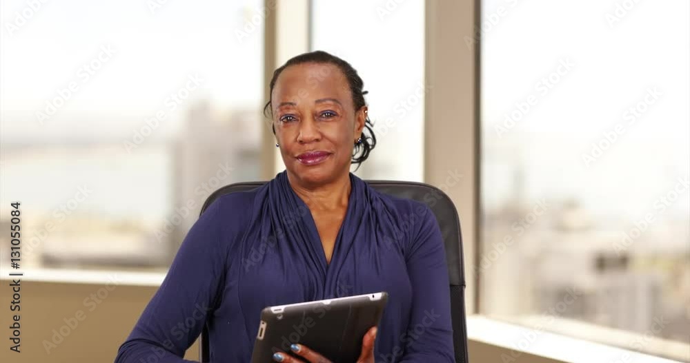 An African American businesswoman poses for a portrait while using her ...