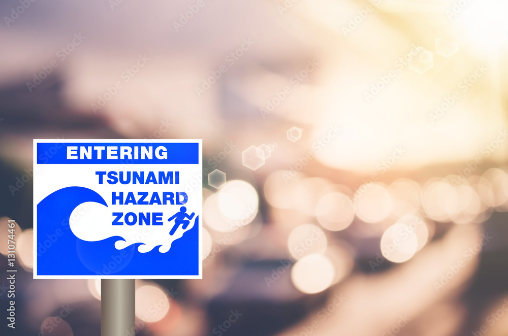 Tsunami hazard zone warning sign on blur traffic road with colorful ...