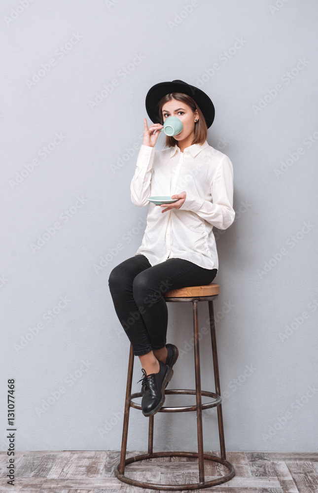 Serious pretty woman sitting on chair and drinking tea Stock Photo ...