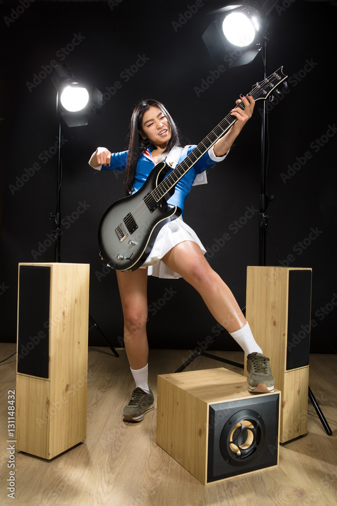 Beautiful Asian rock star lady playing hard rock while posing with ...