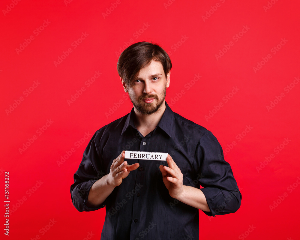 Man holding blank with name of month February. Attractive man shot for ...