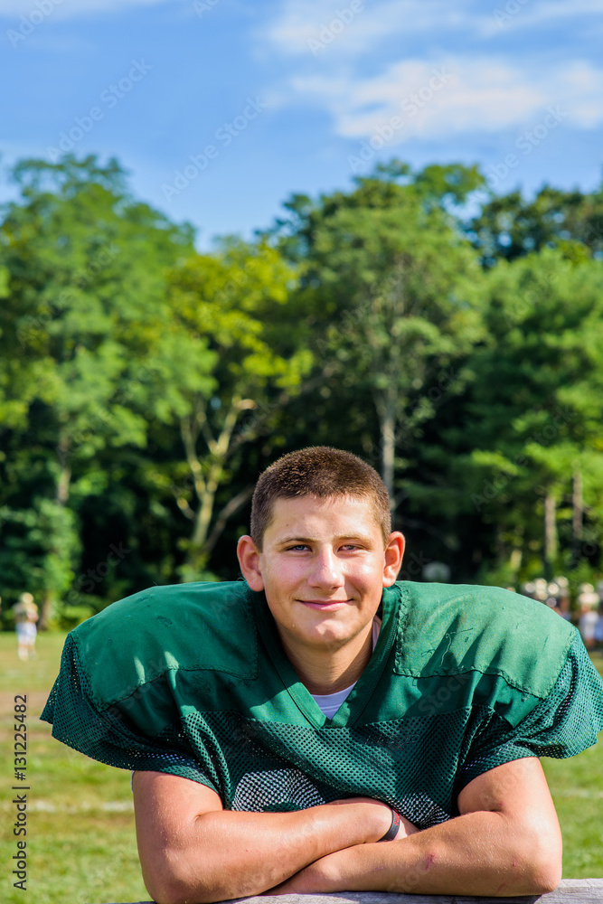 Portrait teenage male American football player with arms folded at ...