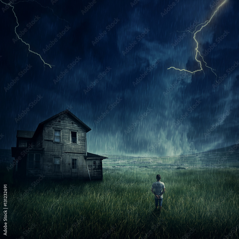 Spooky landscape as a young boy walking in the meadow look at a ghost ...